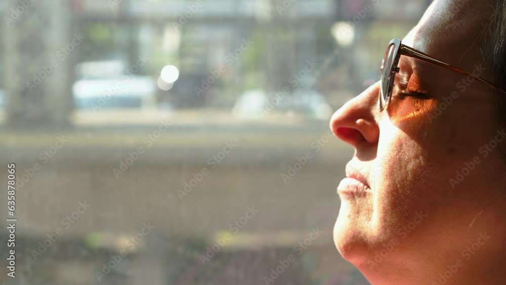 A 52-year-old woman finds solace on a commuter rail. With eyes gently ...