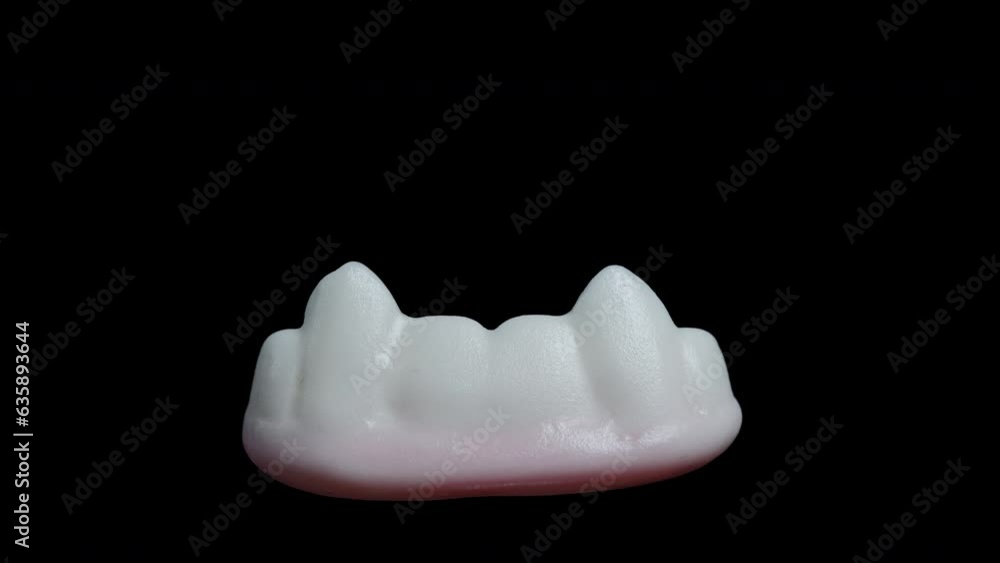 A gummy candy shaped like white teeth and vampire fangs, rotating on a ...