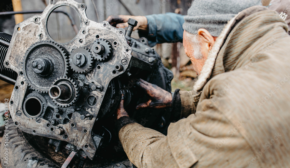 elderly man tuning a car engine at home in a garage, customizing an ...