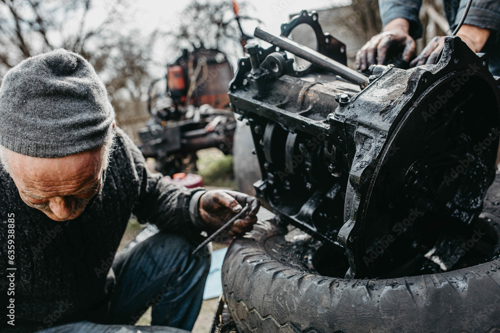 elderly man tuning a car engine at home in a garage, customizing an ...