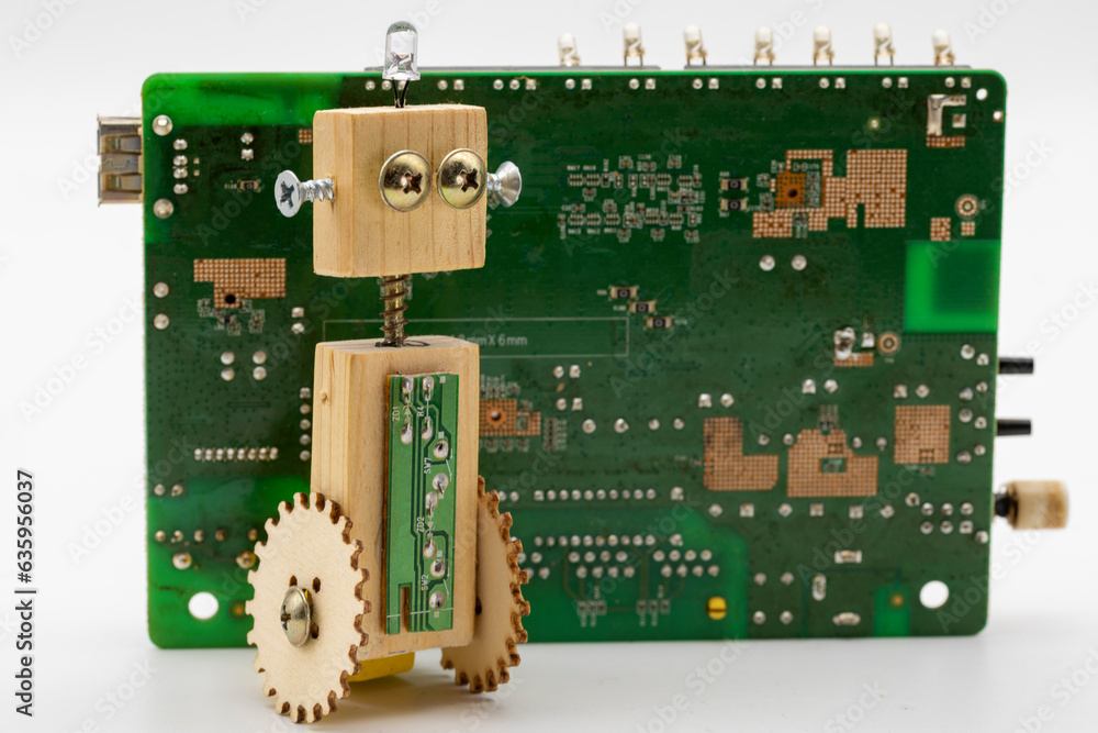 Robot artesanal de madera delante de un panel de circuito electrónico ...