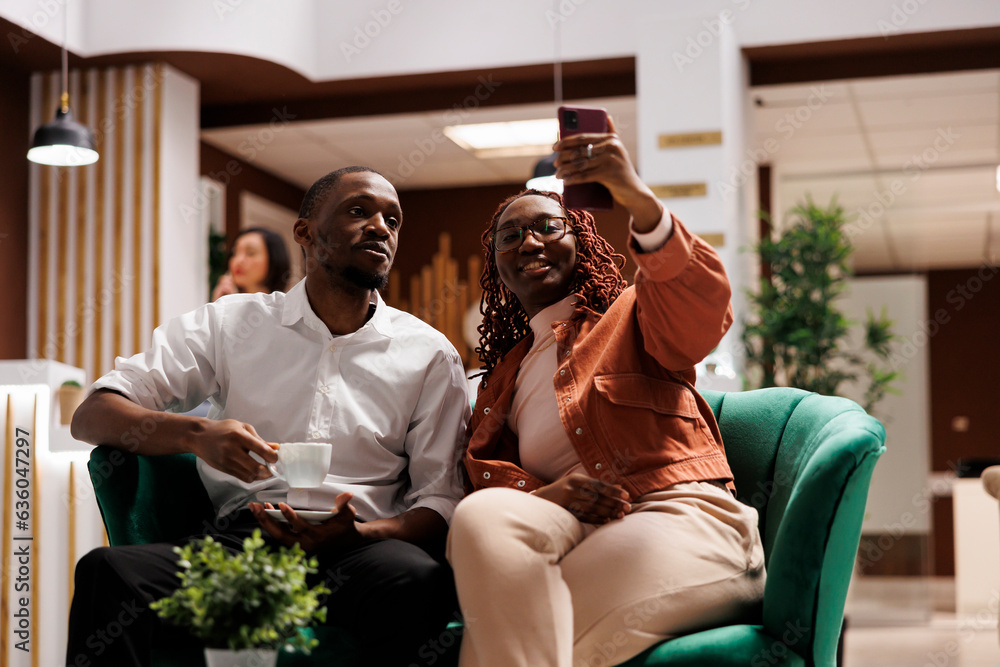 Happy guests taking photos in hotel lobby, relaxing in lounge area ...