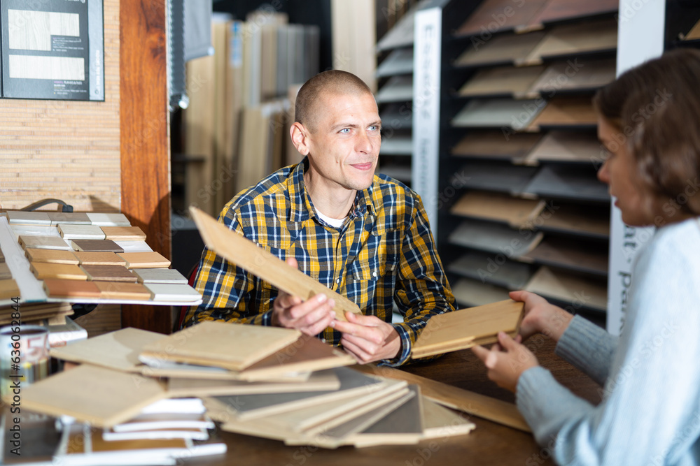Experienced salesman offering laminated flooring to customer in shop of ...