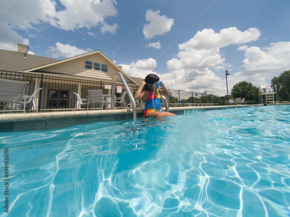 Girl in colorful rainbow swimsuit on ladder at public pool Stock Photo ...