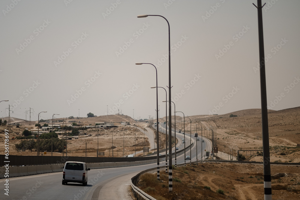 Tall street lights stand over a meandering freeway in the Negev Desert ...