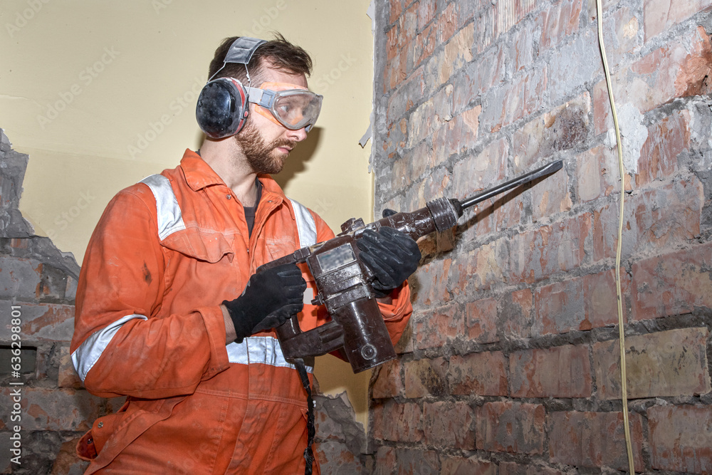 Worker removing old groove for electrical wire with hammer drill ...