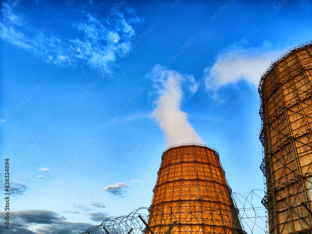CHP cooling towers from which smoke is coming out against blue sky. A ...