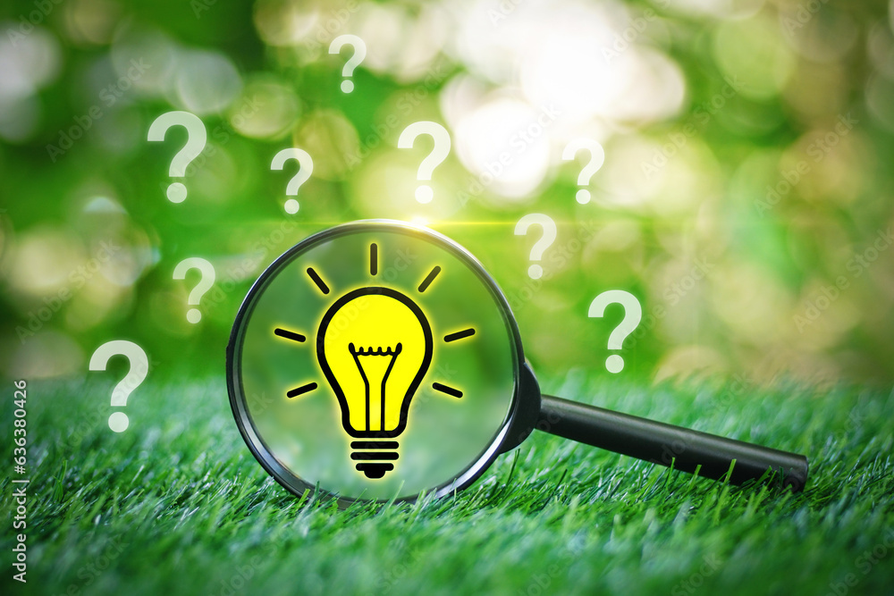 Magnifying glass focused on Light bulb symbol and question mark on the ...