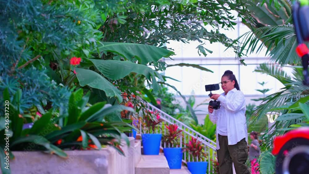 Woman photographer in the exotic jungle greenhouse. Semi professional ...