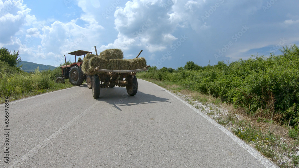 An old tractor, driven by an unrecognizable person, turns off the main ...