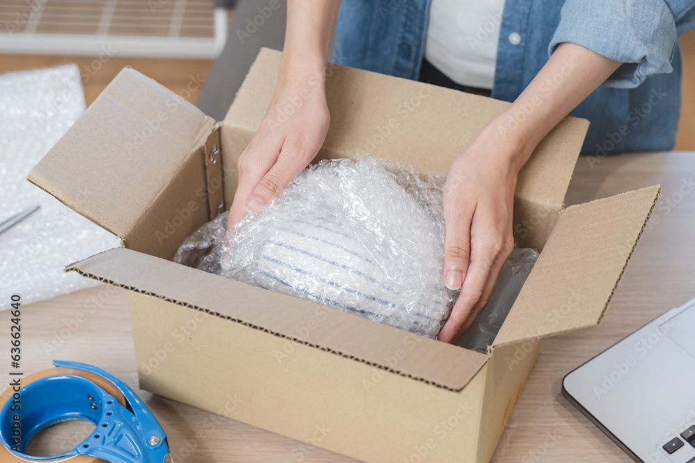 Young Asian woman owner of small online store packing customer orders ...