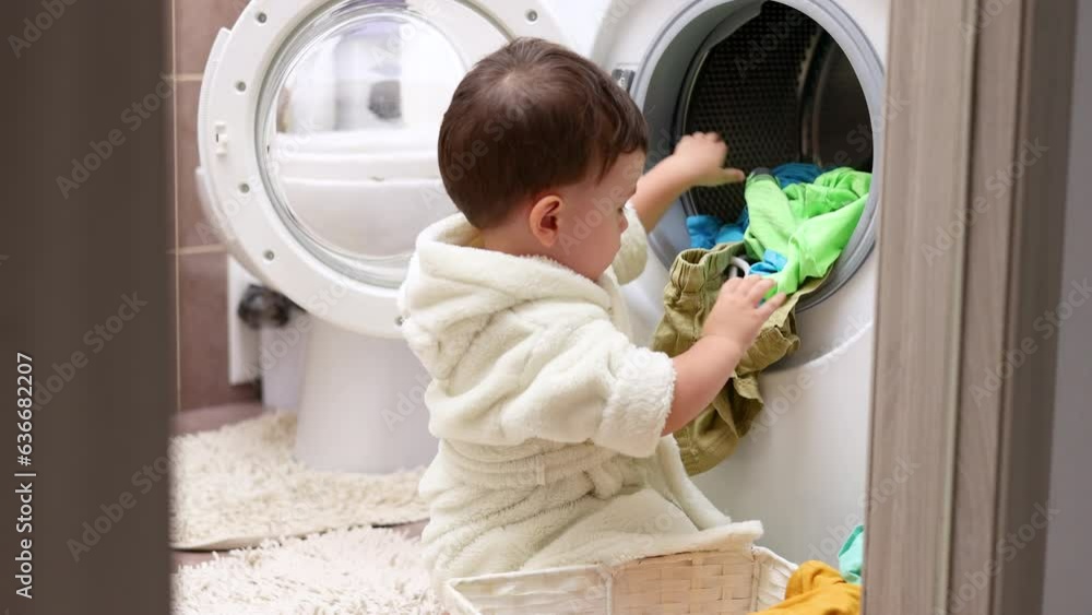adorable cute baby boy in bathrobe putting or remove clothes from ...