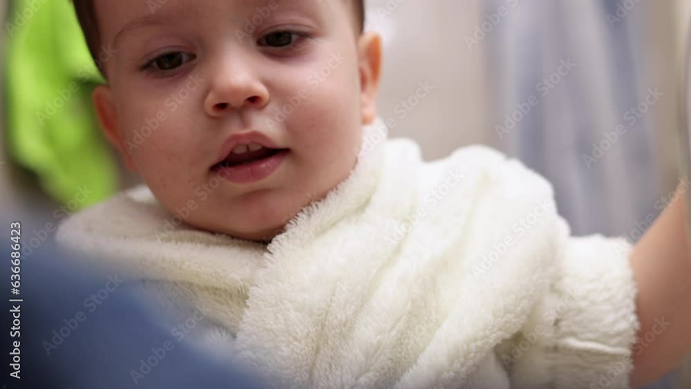 adorable cute baby boy in bathrobe putting or remove clothes from ...