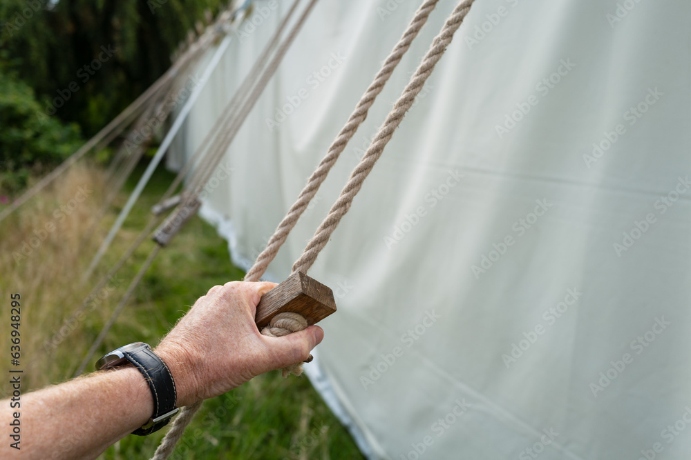 Marquee erector seen adjusting the tension of thick gas ropes on a ...