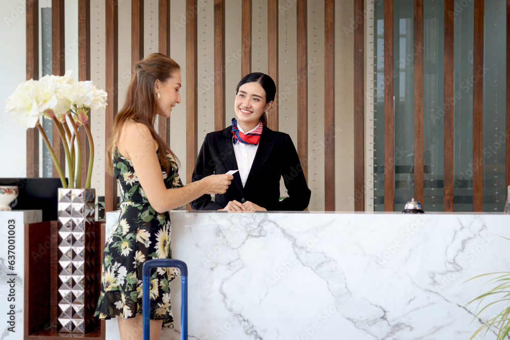 Beautiful smiling Asian female receptionist giving key card to tourist ...