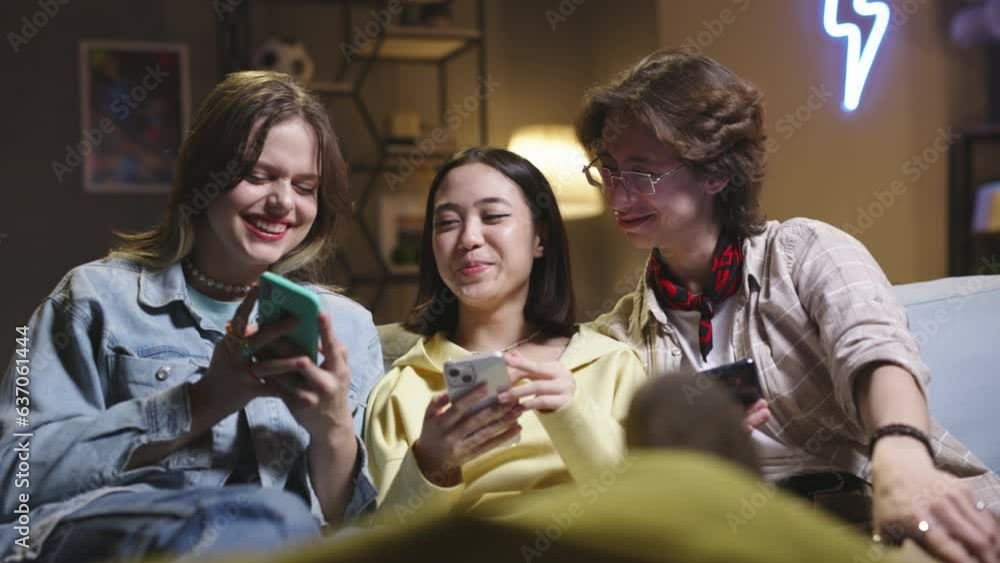 Three happy friends stick to their phones at home. Show each other ...