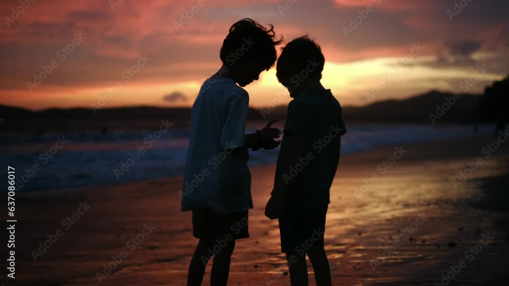 Two siblings, aged 6 and 8, at the sea, beach, during sunset, talking ...