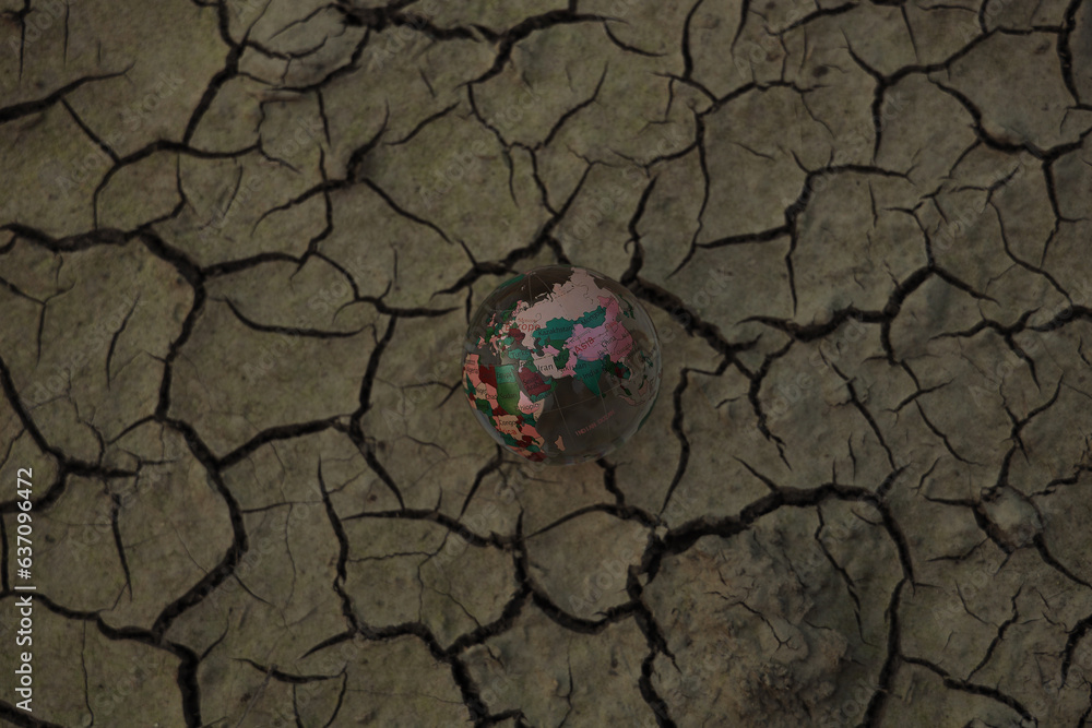Glass globe on black dried crack soil background, top view. Crystal ...