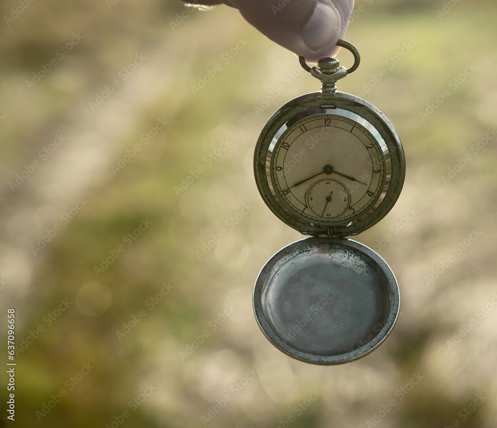 Man looking at traditional opened pocket watch, shot on sunset meadow ...