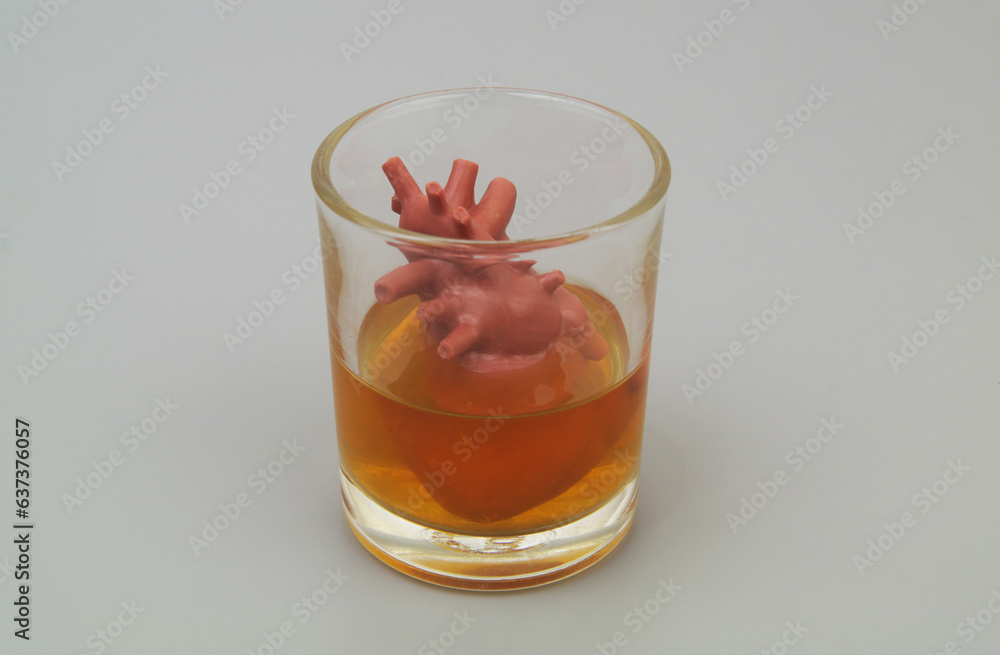 Human heart drowned in glass of alcohol on gray background. Heart ...