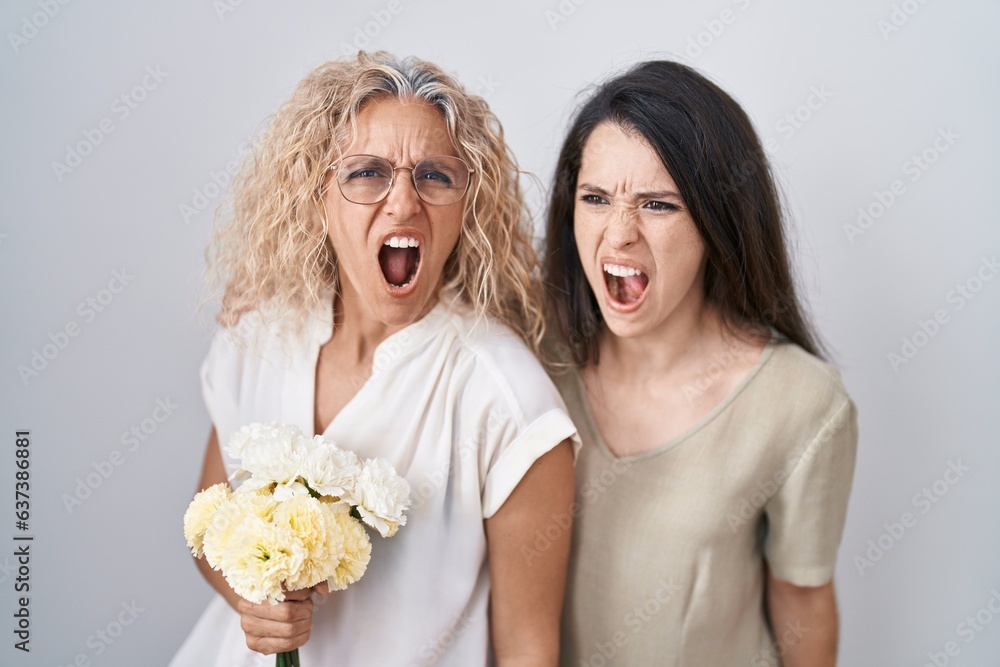 Mother and daughter holding bouquet of white flowers angry and mad ...