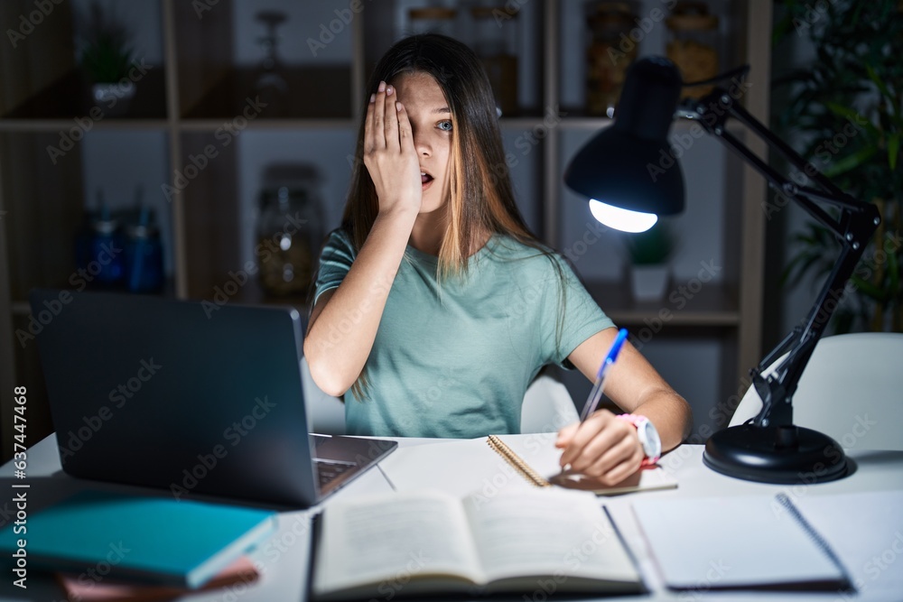 Teenager girl doing homework at home late at night yawning tired ...