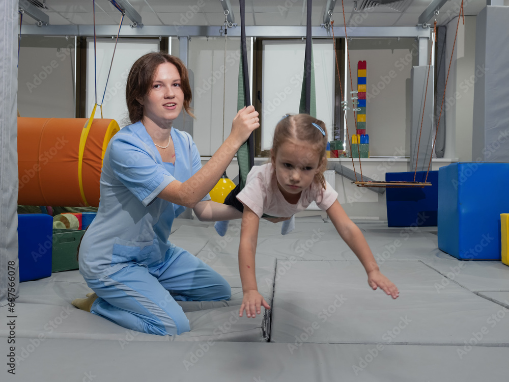 Child with physiotherapist on swing during sensory integration session ...