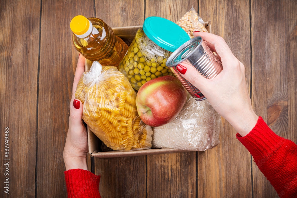 Woman filling in food donation box. Pasta, cereals, various canned food ...