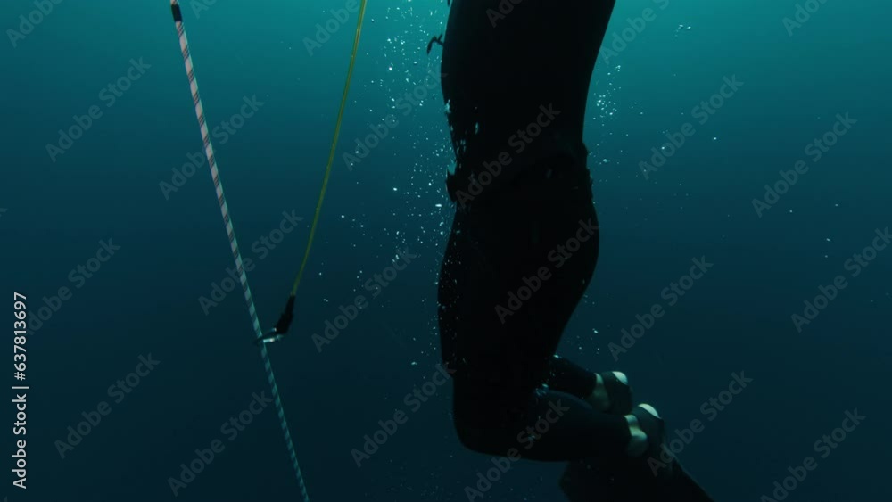 Freediving on the rope in a sea. Male freediver ascends along the rope ...
