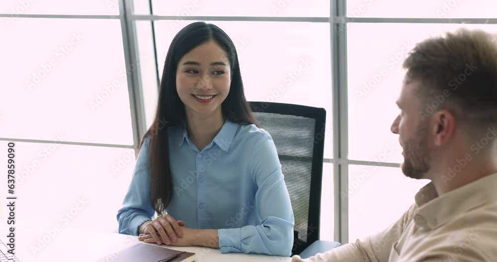 Asian and Caucasian teammates talking during meeting in company office ...