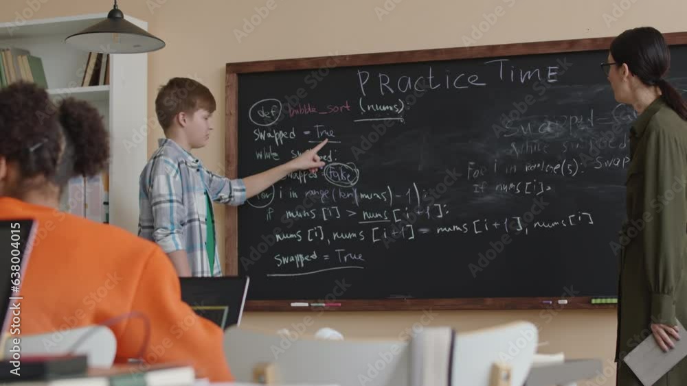 Medium shot of Caucasian teenage schoolboy answering at blackboard ...