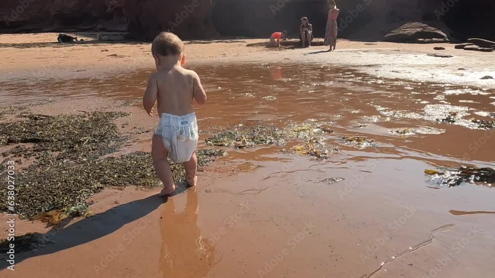 Toddler girl wearing diaper that is big and saggy on beach on bright ...