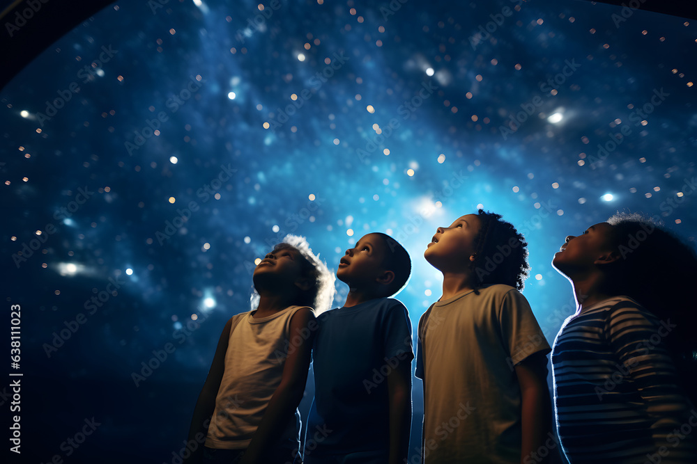 Group of children gazing up at a planetarium ceiling full of stars ...