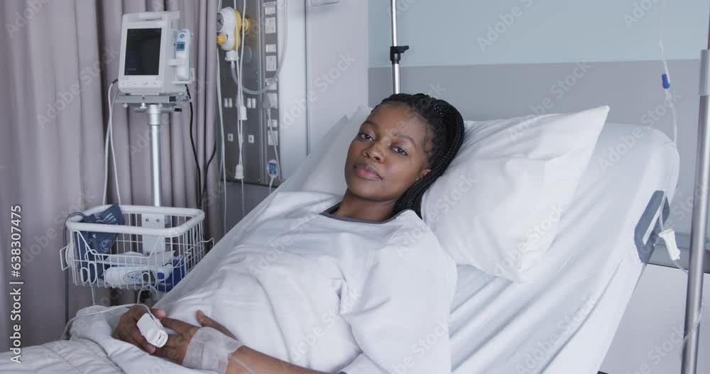 Happy african american female patient lying in bed in hospital room ...