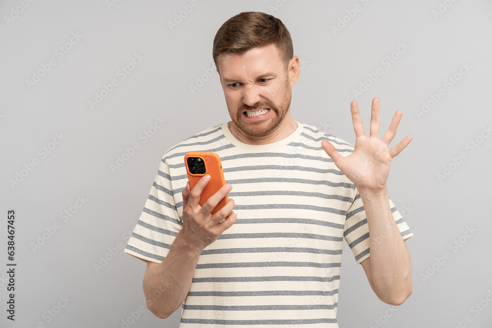 Young man with disgust look at smartphone screen. Portrait of guy ...