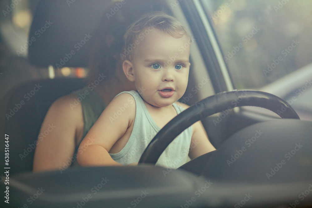 child sitting on mother's knees in the car and turning steering wheel ...