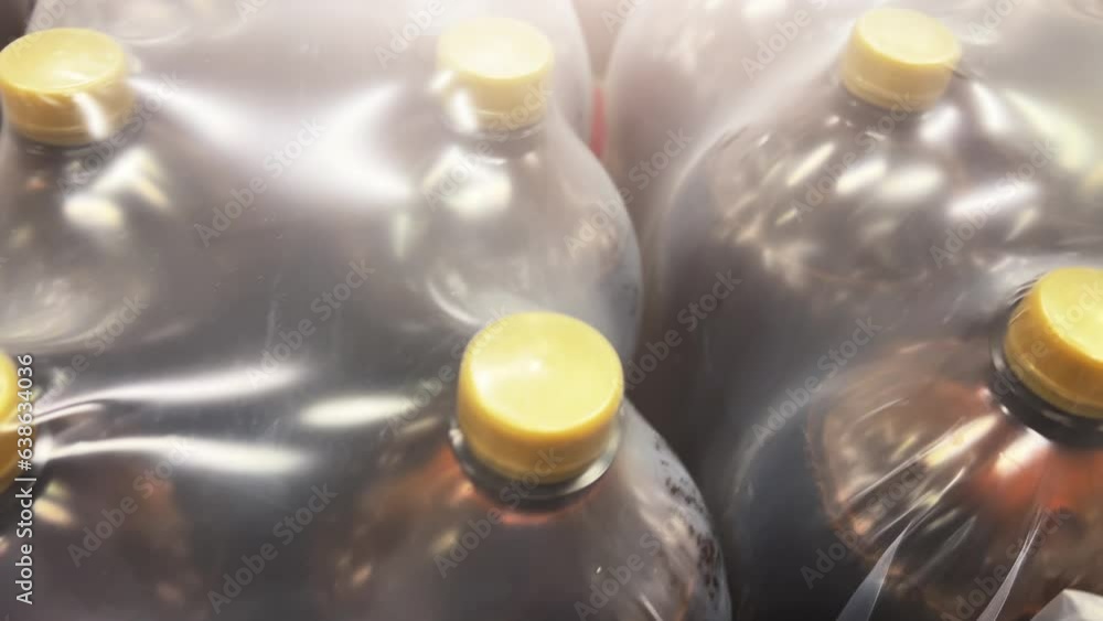 Rows of brown plastic two-liter bottles with beer or soda, packed in 6 ...