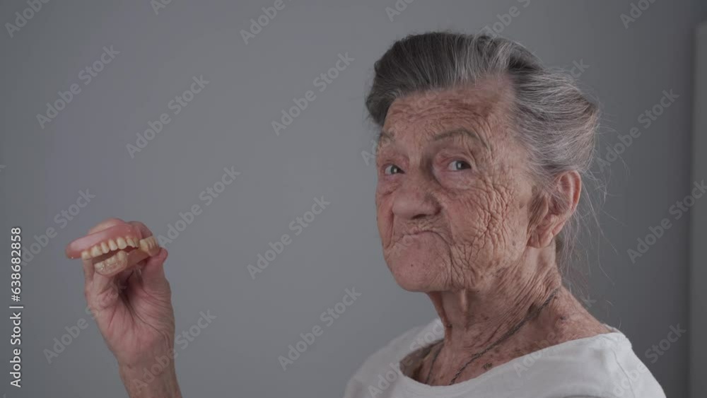 Dental prosthesis in the hands of satisfied senior woman with gray hair ...