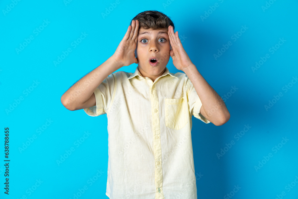 Beautiful kid boy wearing casual shirt with scared expression, keeps ...