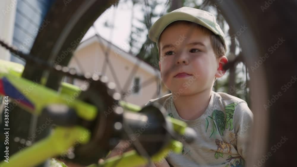 curious little boy pedaling a bicycle with his hand and watching the ...