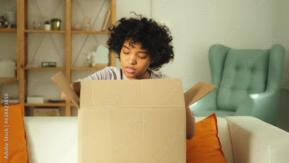African girl unpacking delivery looking in box. Happy woman opening ...