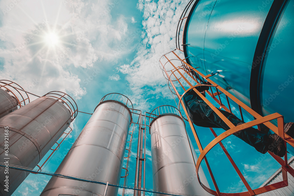 Male worker climbs up the ladder inspection stainless tank work at ...