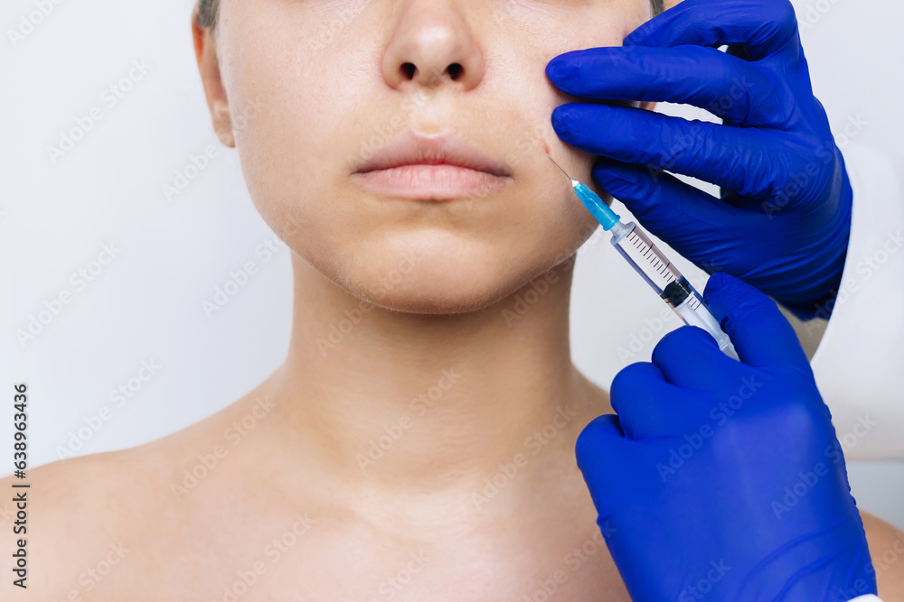 Doctor's hands in blue gloves inject the fillers into nasolabial ...