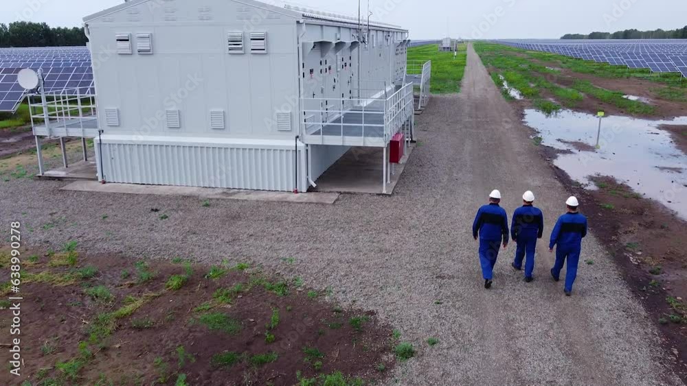 New solar farm under the blue sky. Workers in special outfit walk and ...