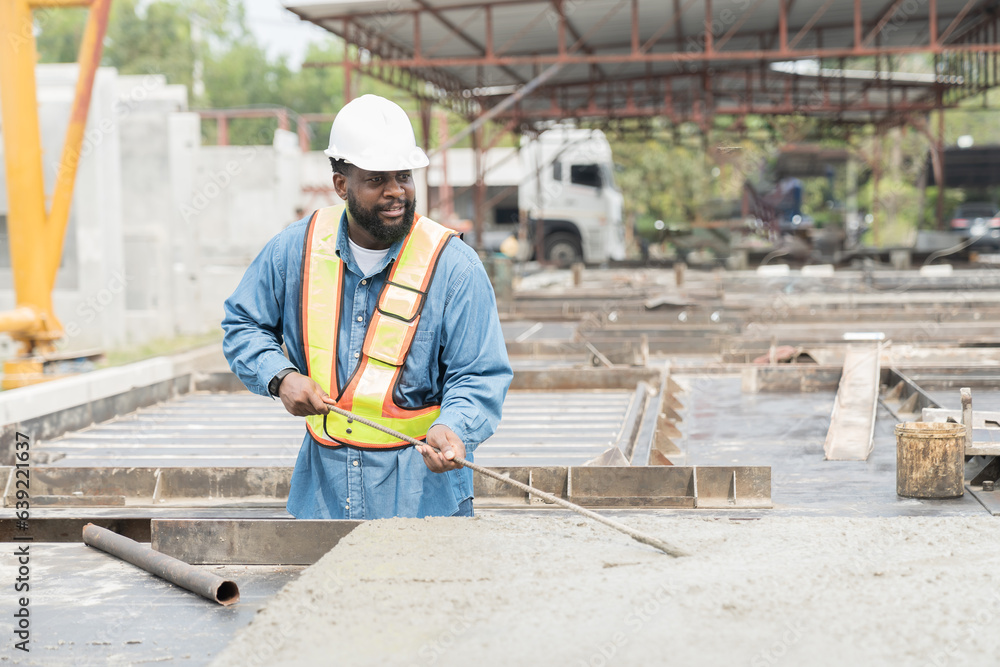 Construction worker uses long steel trowel spreading wet concrete ...