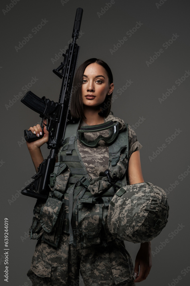 Beautiful female soldier in military uniform stands holding an ...