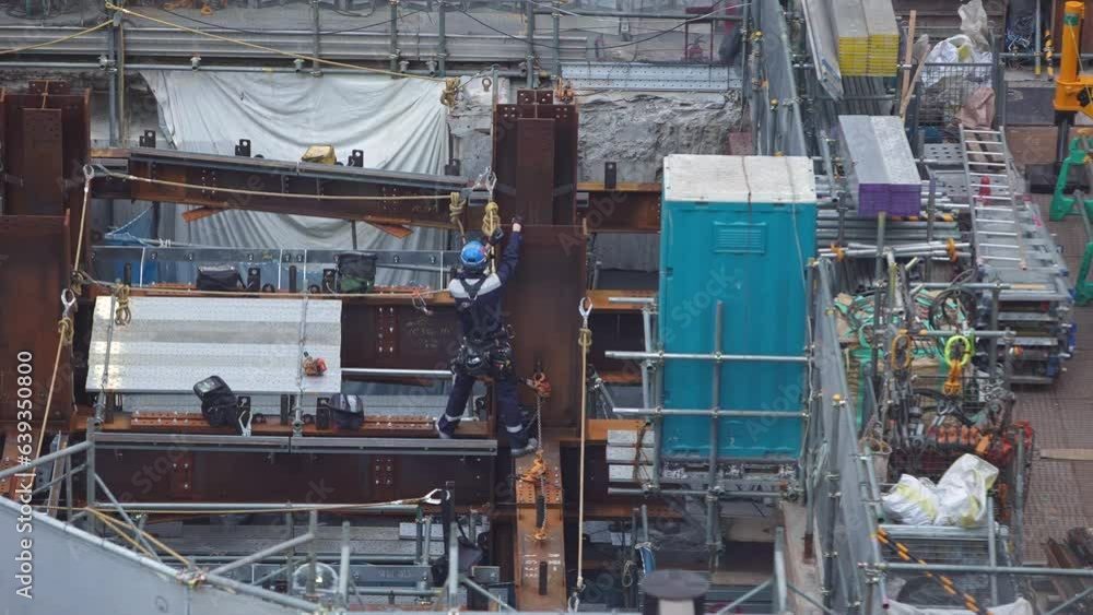 Slowmotion elevated view of man works on construction site, stands on ...
