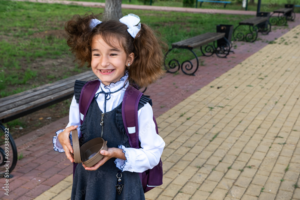Girl with backpack eating sandwich packed in a sandwich box near school ...