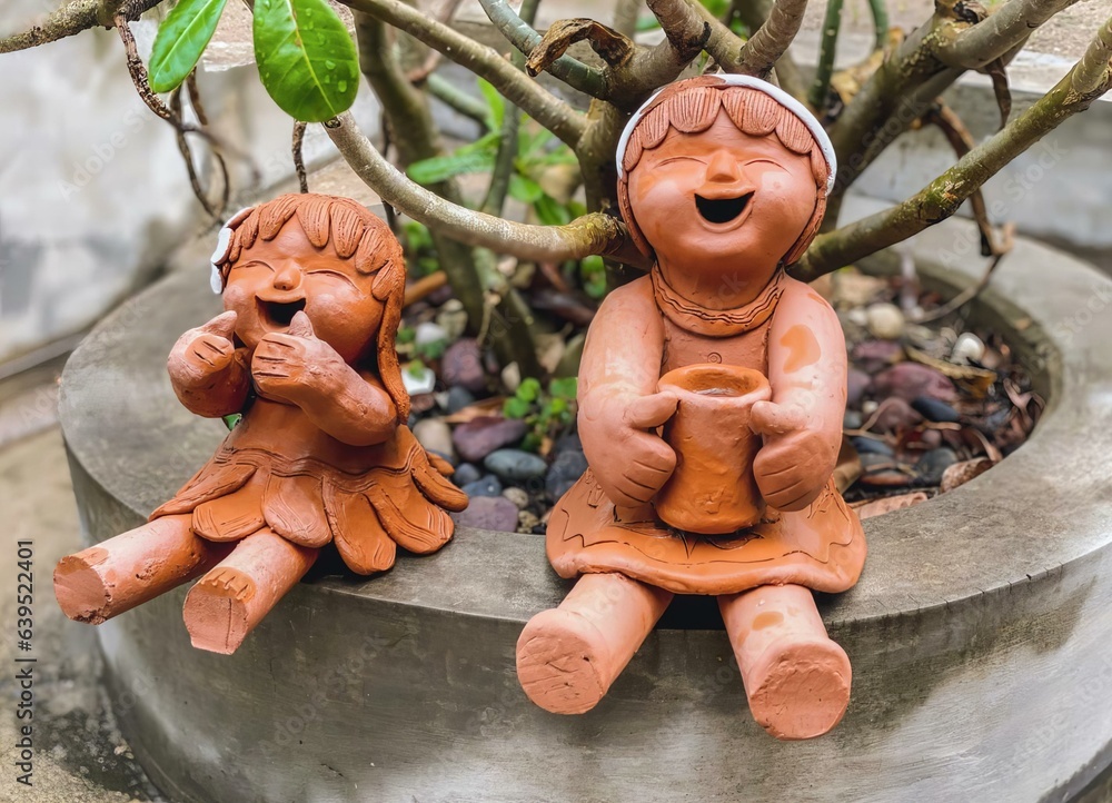 a photography of two clay figurines of a woman and a child, flowerpot ...