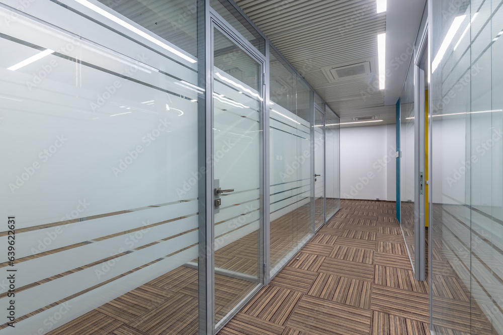 A corridor in a modern office with a space divided into cubicles with ...